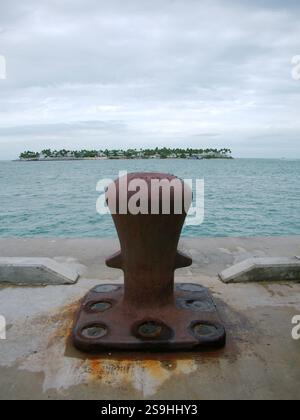 A very old, rusty iron bollard on a concrete pier by the river. Pier at ...