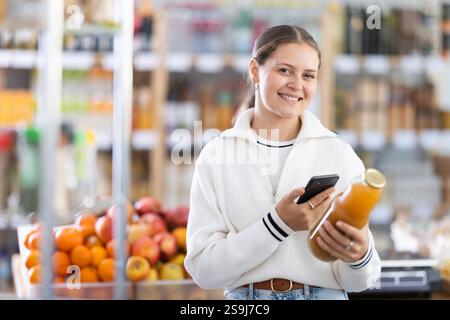 Supermarket visitor buying fruit juice with qr code Stock Photo - Alamy