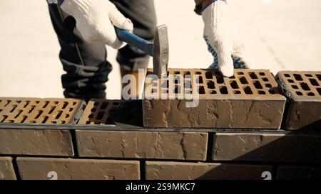 Worker is carefully placing bricks on surface while using trowel to ...