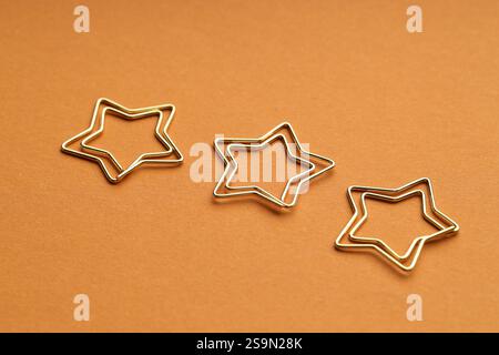 Star shaped paper clips on orange background, flat lay. Space for text ...