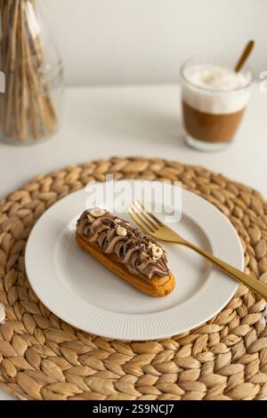 Plate with tasty chocolate eclairs and cup of coffee on wooden ...