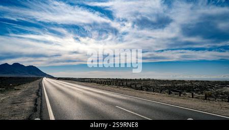 Long empty road stretches into desert landscape under clear blue sky ...