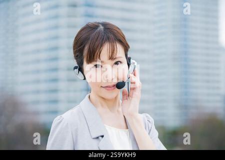 Asian (Japanese) female operator wearing headphones with microphone in business district Stock ...