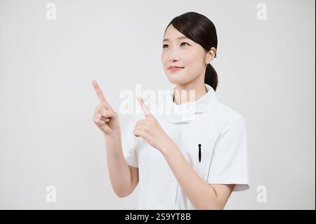 Woman in white coat striking a pointing pose Stock Photo - Alamy