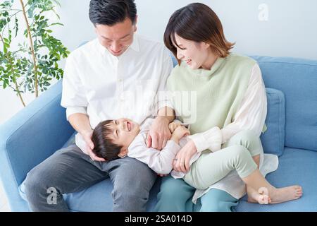 Child being pampered by parents on a sofa Stock Photo - Alamy