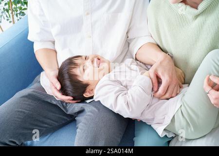 Child being pampered by parents on a sofa Stock Photo - Alamy