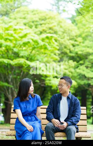 Young couple chatting on park bench, back view Stock Photo - Alamy