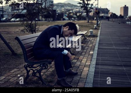 Businessman drooping on park bench Stock Photo - Alamy