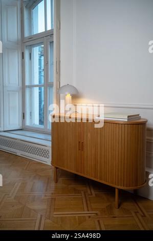 Chest of drawers, floor lamp and table in interior of living room Stock ...