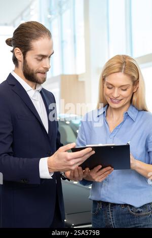 Blonde female customer signing the contract with dealership ...
