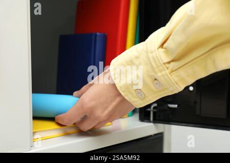 Woman putting school supplies into locker, closeup Stock Photo - Alamy