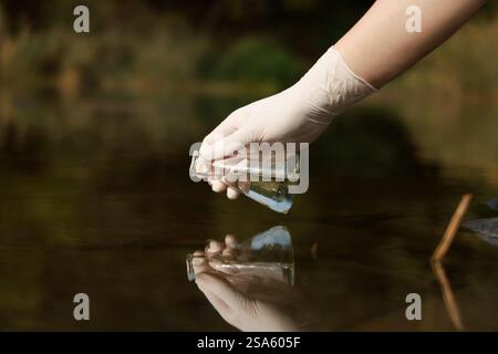 Examination of water quality. Researcher taking water sample from lake ...