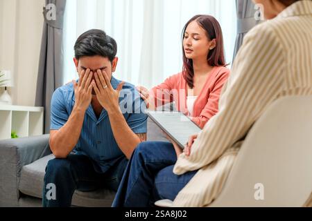 distressed asian man covers his face with his hands during a couple's ...