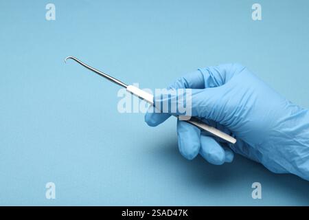 Doctor with surgical hook on light blue background, closeup. Space for ...