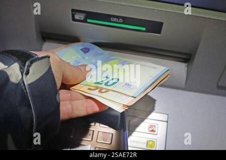 Bargeldversorgung aus einem Automat Eine Person holt an einem Geldautomaten Bargeld in 50 und 20 ...