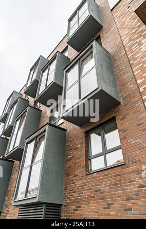 Modern residential building with gray brick facade, red vertical ...