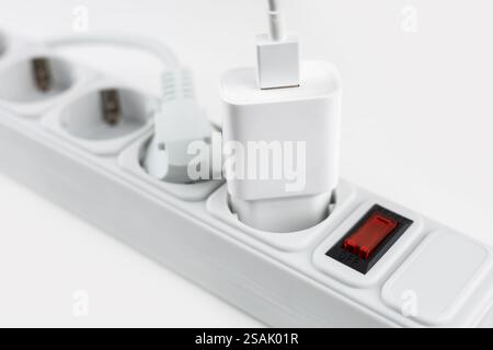 mobile phone chargers connected to electrical power strip. Various ...