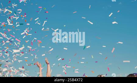 High school graduates joyfully tossing vibrant confetti in the air to ...
