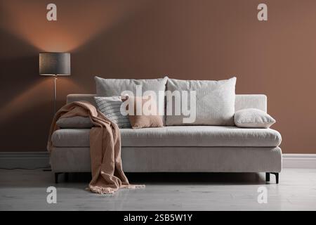 Stylish interior in mocha mousse shade. Armchair, pouf and wall in ...