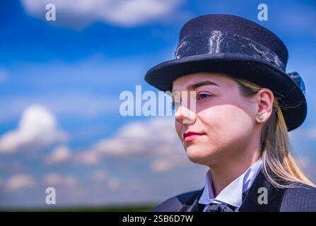 A young pretty lady funeral director in traditional attire with top hat ...