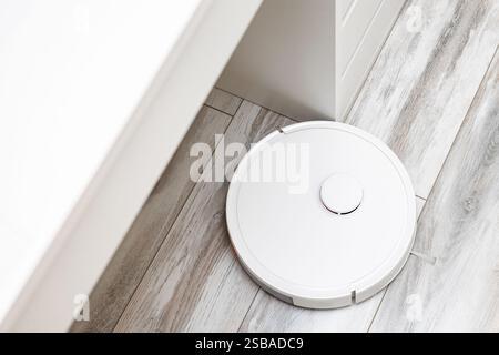 Modern robot vacuum cleaner near sofa in room Stock Photo - Alamy