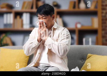 Asian man feeling unwell and resting on sofa at home Stock Photo - Alamy