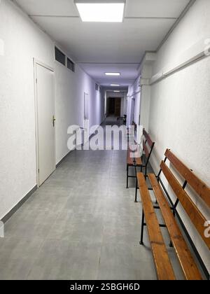 A spacious, well-lit hallway featuring sleek white doors, light wooden ...