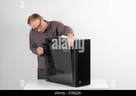 Man removing tempered-glass left panel from PC case, empty big tower ...