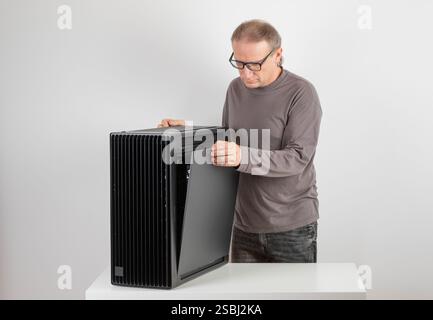 Man removing metal right panel from PC case, empty big tower, chassis ...