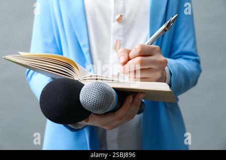 Journalist with microphones taking notes on grey background, closeup ...