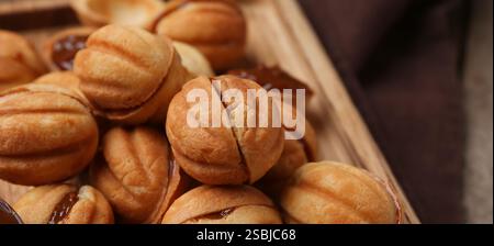 Many sweet walnut shaped cookies with boiled condensed milk on brown ...