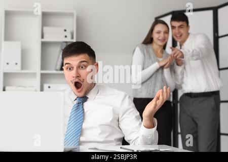 Shocked young man with drawn mustache and his colleagues in office ...