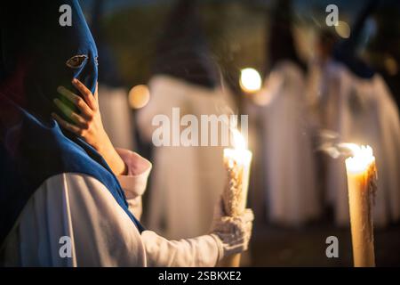 A nighttime procession featuring penitents with traditional outfits ...
