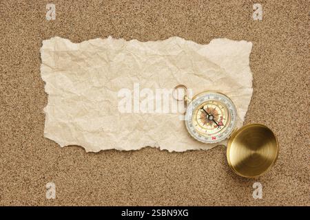 Compass on old sheet crumpled paper against the background of sand ...