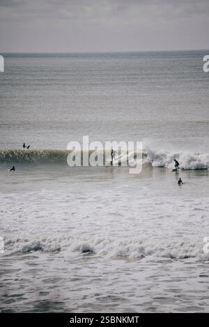 A group of surfers riding the waves in the sea in New England Stock ...