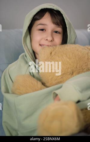 The boy embraces a soft teddy bear, evoking themes of childhood ...