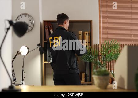 Male FBI agent taking folder from shelf in office, back view Stock ...