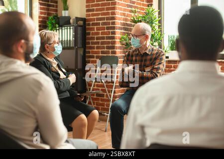 Therapist holding clipboard and listening to patient at therapy session ...