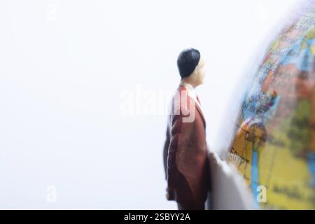 Businessman figure observing a globe model from close-up Stock Photo ...