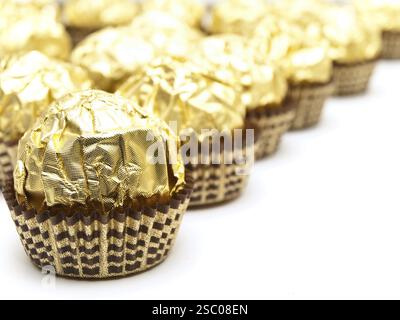 Rows of candies in gold paper over the white background Stock Photo - Alamy