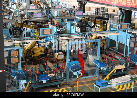 A worker produces auto parts at the production line of Wuxiang Auto ...