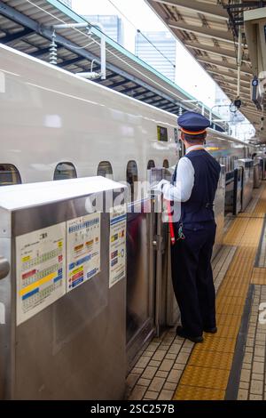 Station staff on the platform of the Shinkansen train at Shin-Osaka ...
