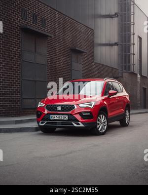 Red SEAT Ateca in front of modern building. Front three quarter view of ...