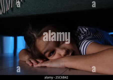 Fearful girl hiding under bed at night Stock Photo - Alamy