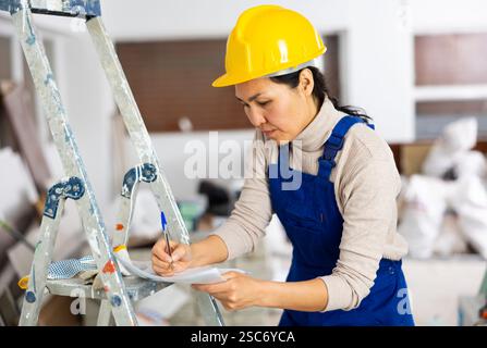 Woman in overalls signs an act of acceptance of completed work Stock ...