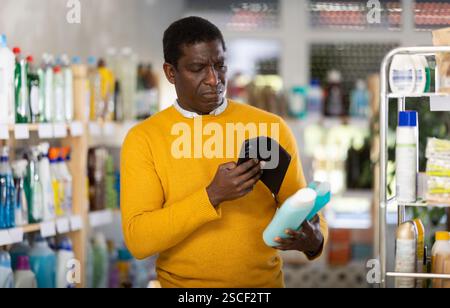 Checking expiration date of shampoo or shower gel - male shopper scans QR code on label of ...