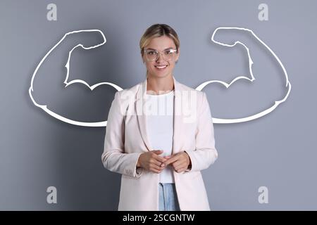 Confident beautiful woman with drawing of strong arms behind her on ...