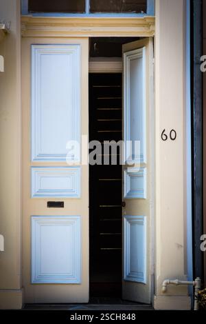 A vertical shot of an open vintage wooden door leading to stairs inside ...