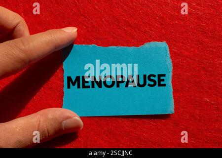 Menopause message written on ripped torn pink paper on brown background ...