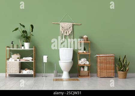 Toilet bowl, shelving units and laundry basket near beige wall in ...